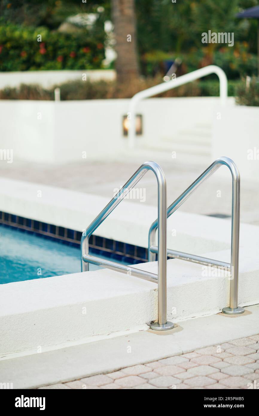 outdoor swimming pool with bright blue water and metallic pool ladder ...