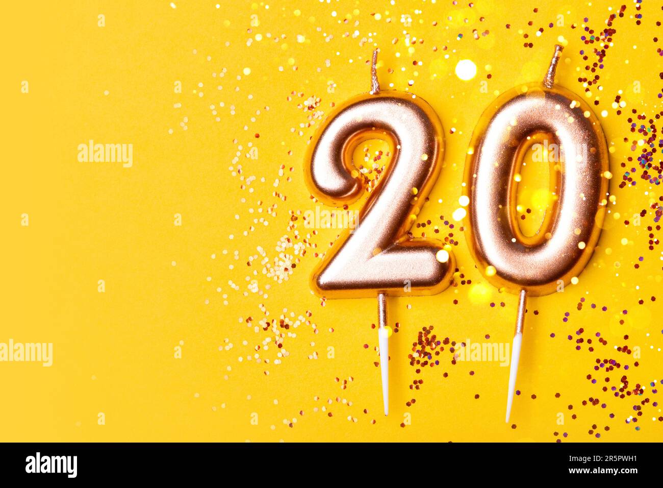 Gold candles in the form of number twenty on yellow background with ...