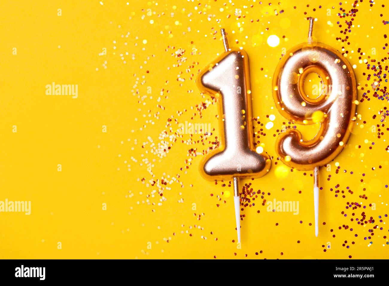 Gold candles in the form of number nineteen on yellow background with ...
