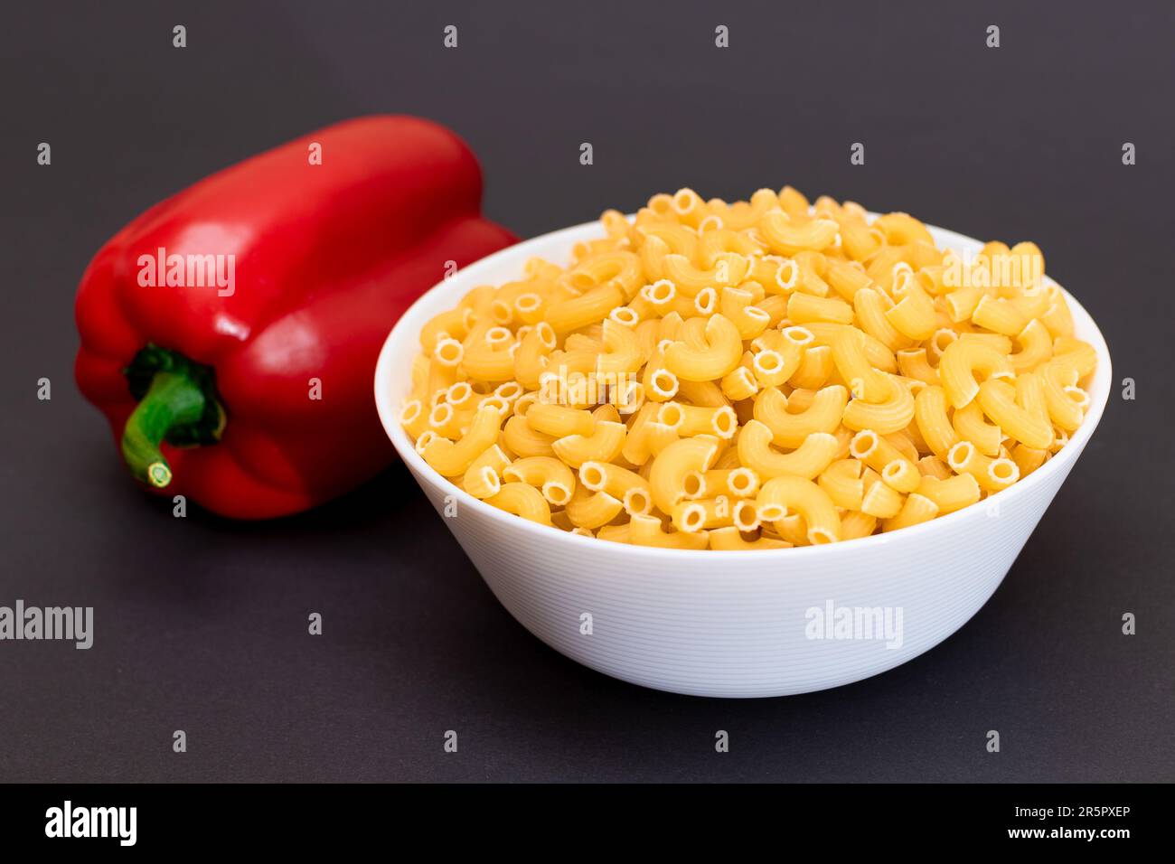 Uncooked Chifferi Rigati Pasta in White Cup and Red Bell Pepper on ...