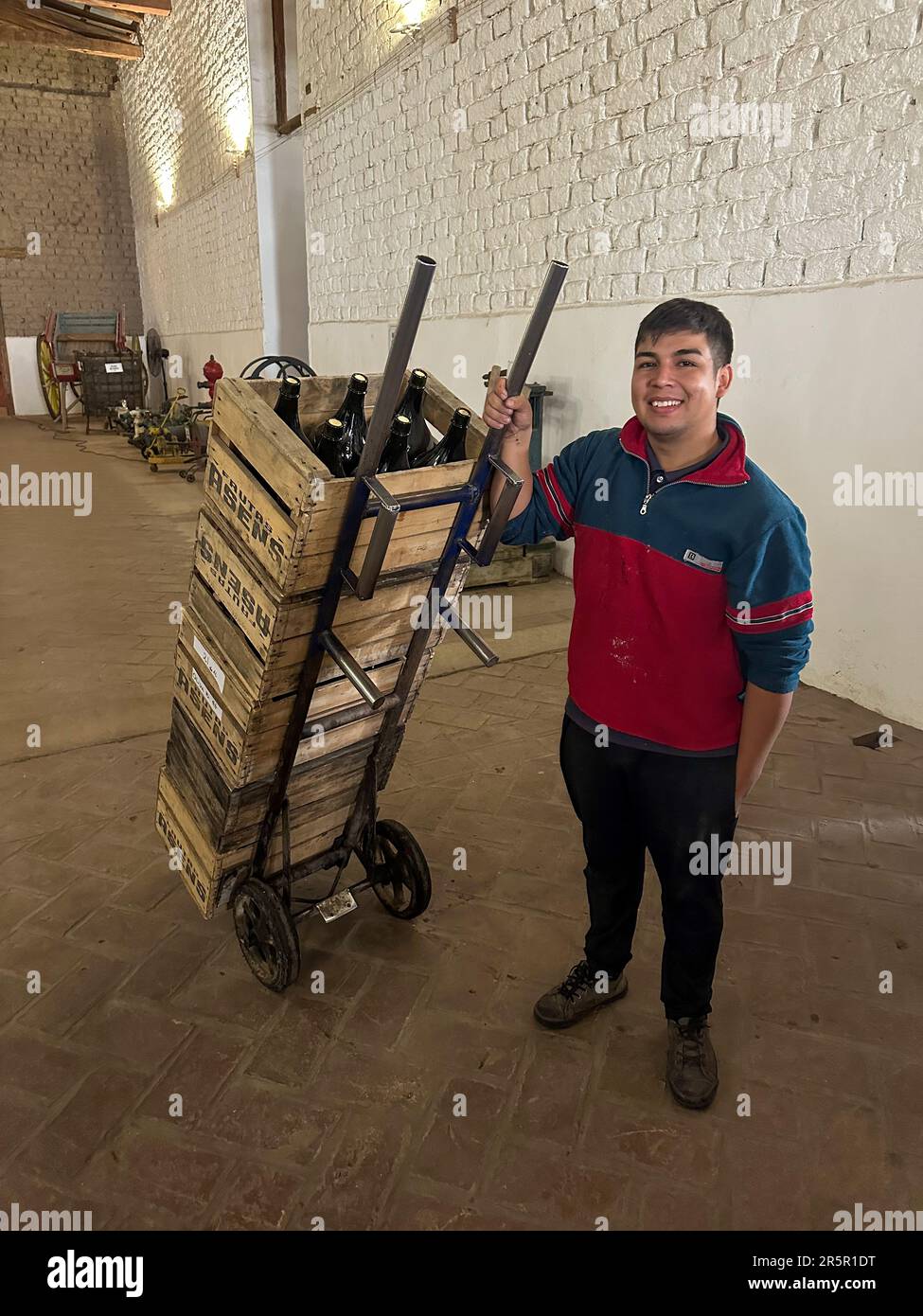 A worker moves a load of large wine bottles at La Abjea Winery, San ...