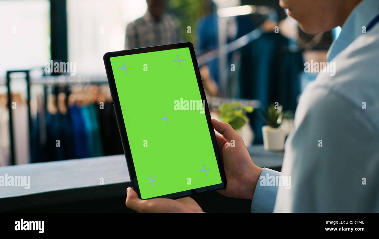 Asian store worker holding chroma key green screen mock up tablet ...