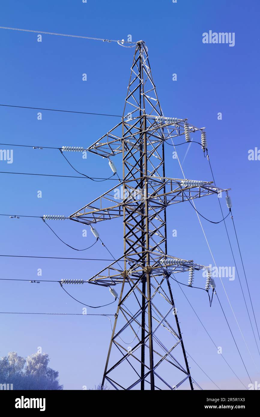 Frost-covered power line pylon on a clear frosty day against a blue sky ...