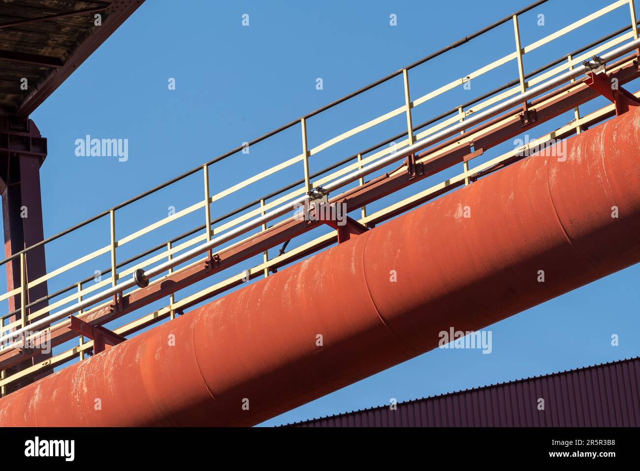A steel staircase with a handrail winding upwards along a metal pipe ...