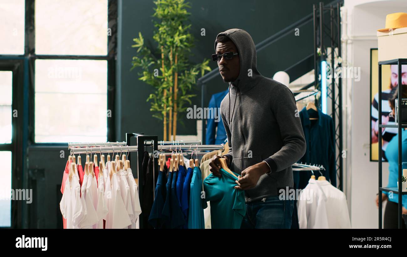 African american robber stealing trendy clothes in modern boutique ...