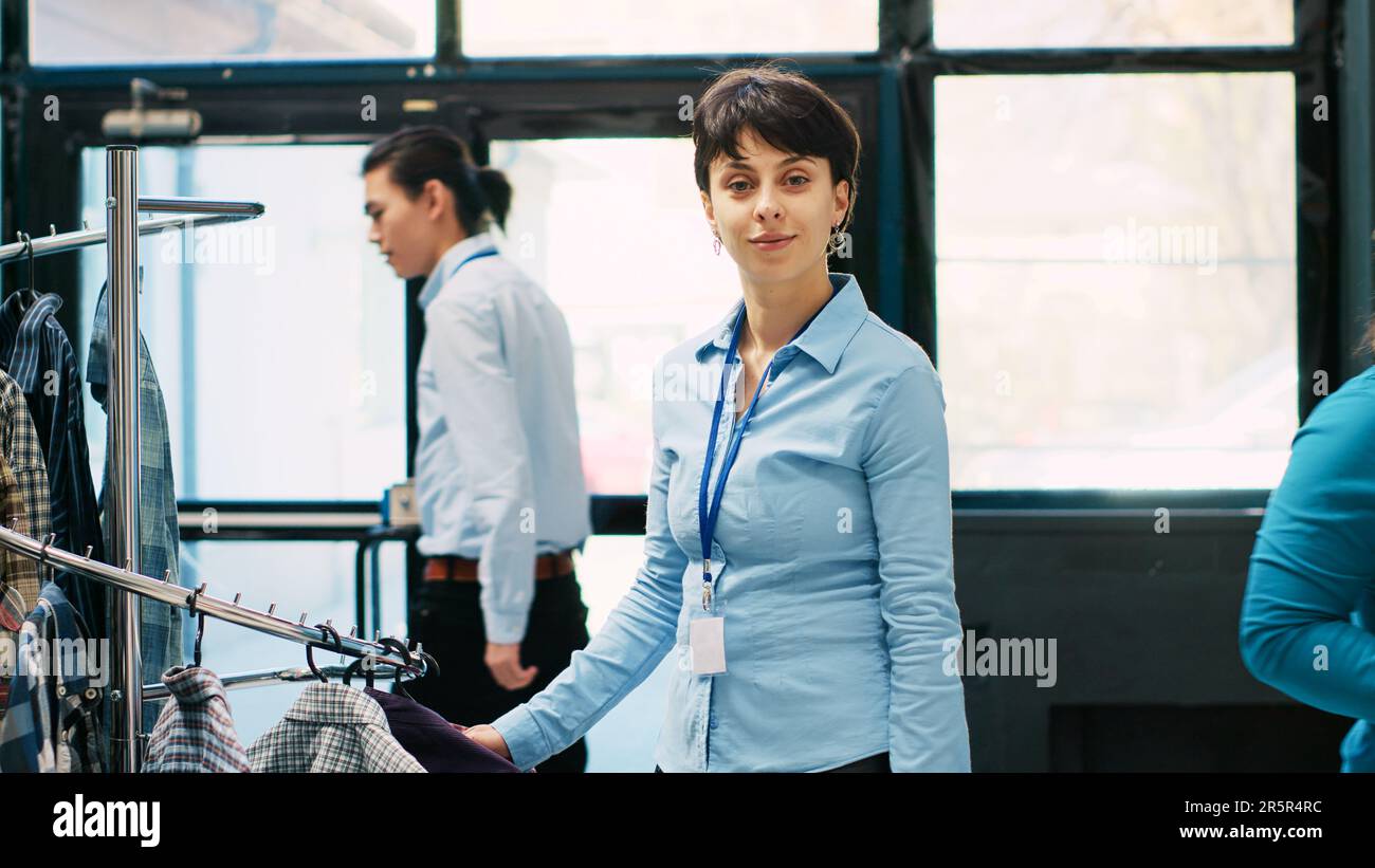 Worker arranging stylish clothes in modern boutique, working at ...