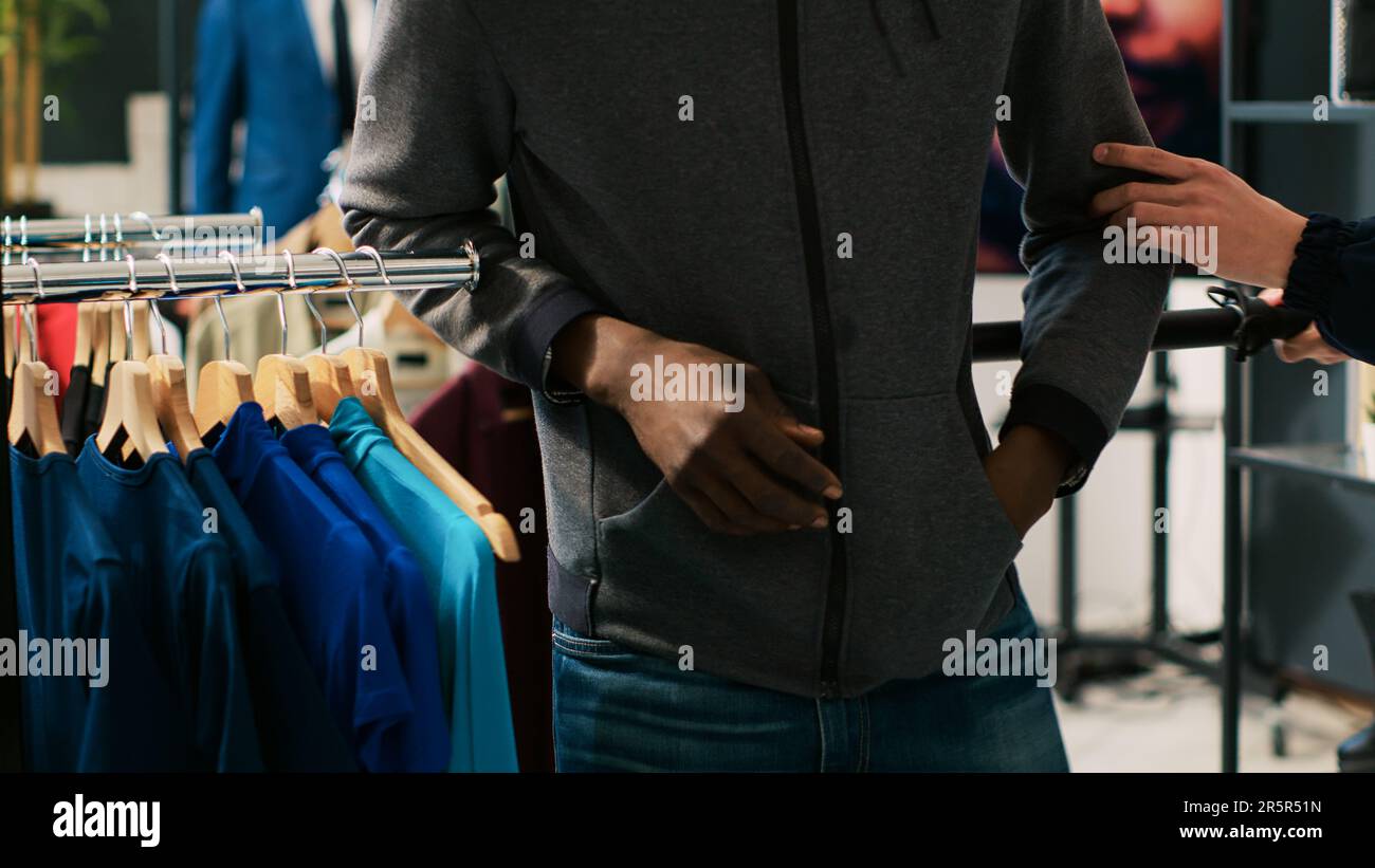 Thief trying to stole fashionable shirt in modern boutique, wearing ...