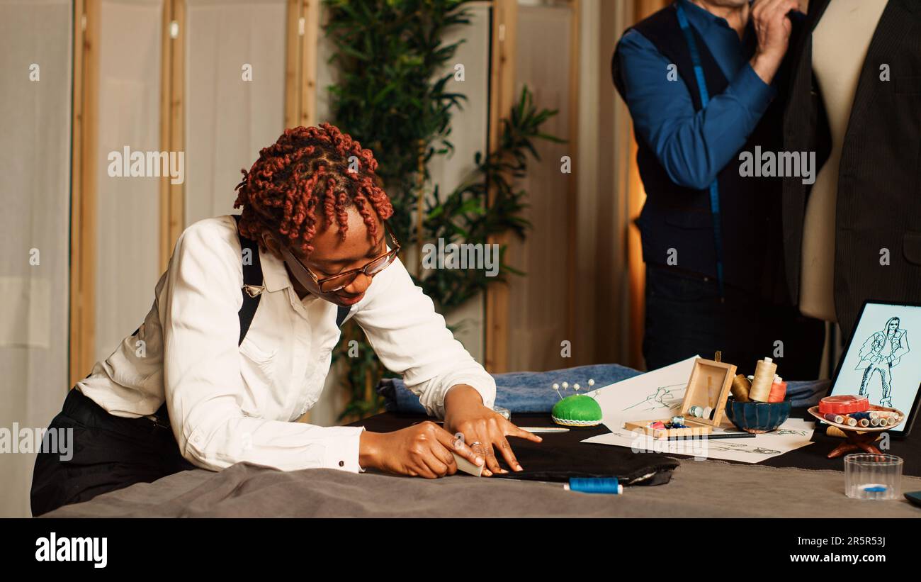 Apprentice measuring fabric in atelier, learning to create clothes from ...