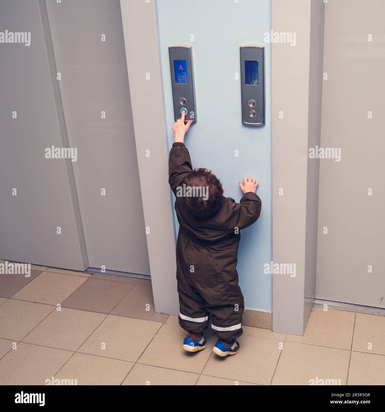 A small child presses the elevator call button. Baby reaches for the ...