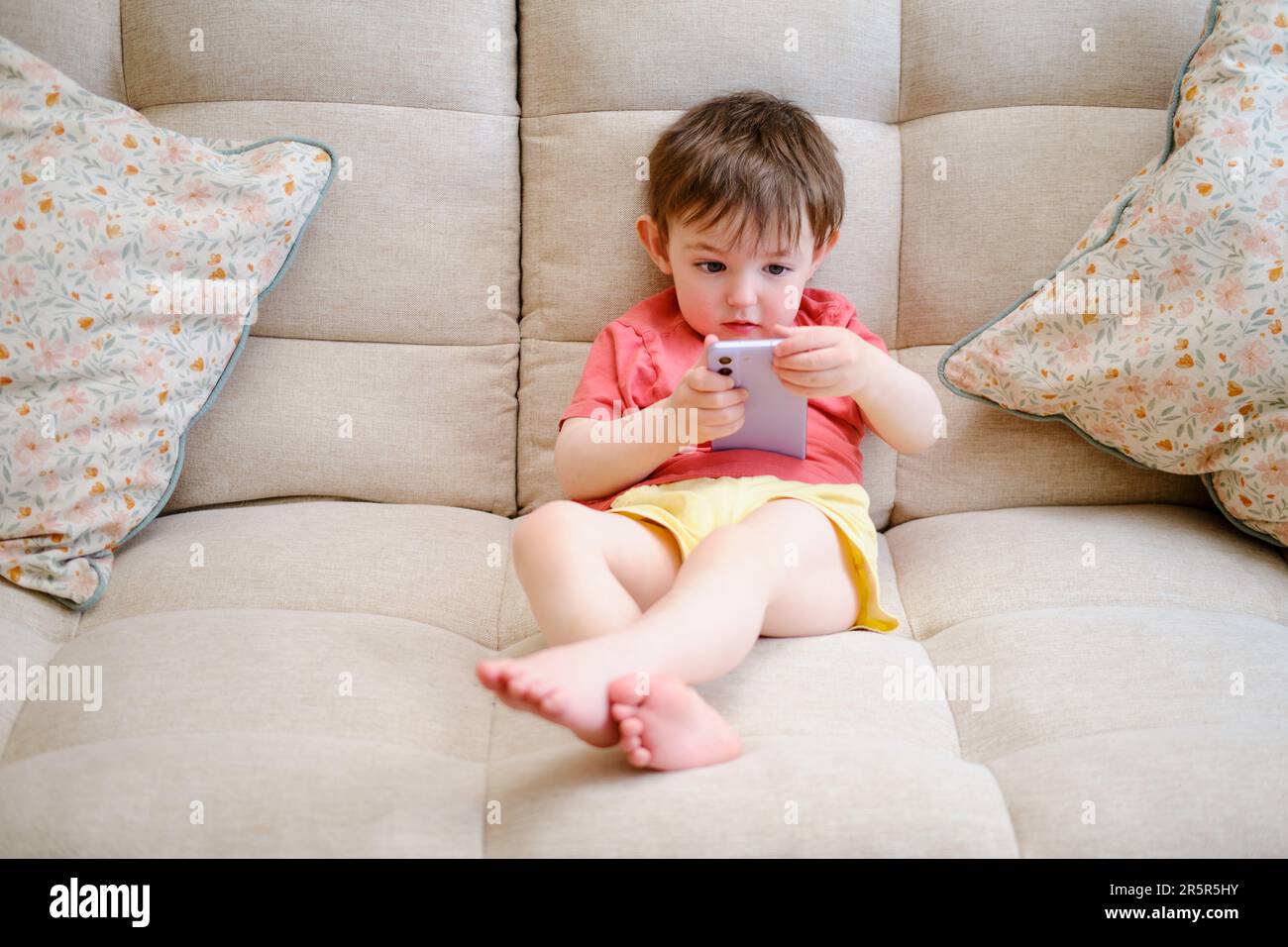 Toddler baby is tapping away on the mobile phone screen. The happy ...