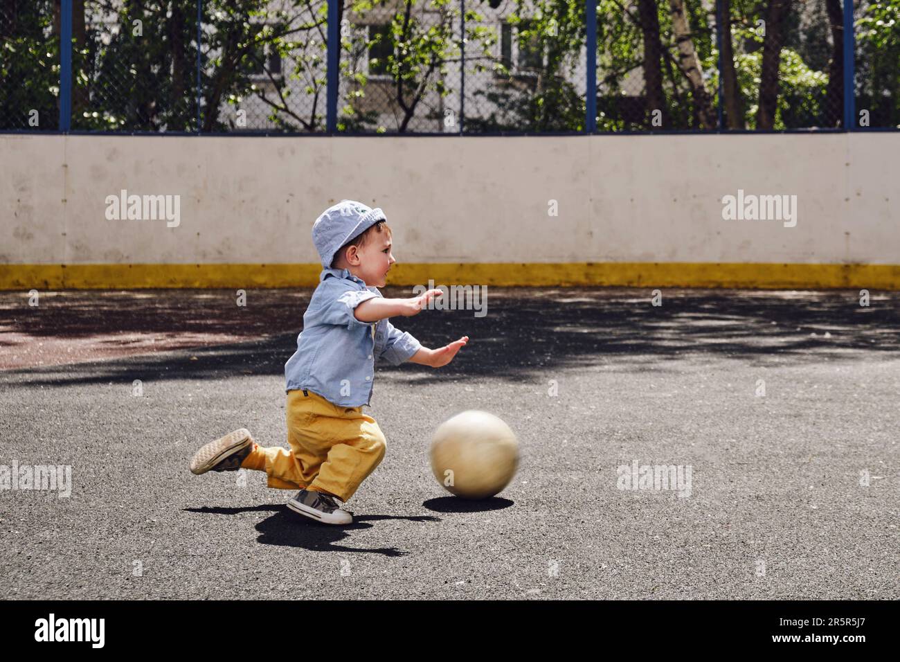 A child falls while playing with a ball on a football field. Kid aged ...