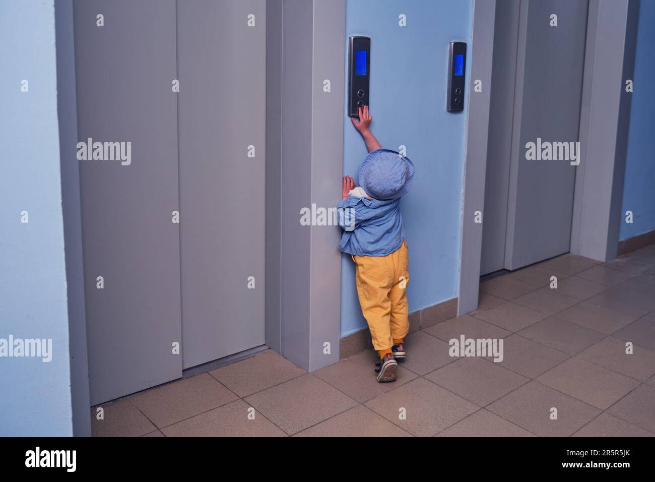 Toddler baby calls the elevator by pressing the button in the entrance ...