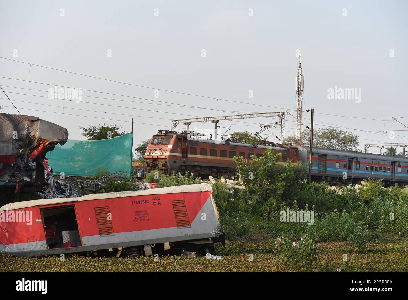 Balasore. 5th June, 2023. A passenger train passes by the site of a ...