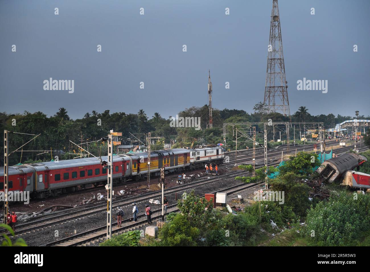 Balasore. 5th June, 2023. A passenger train passes by the site of a ...