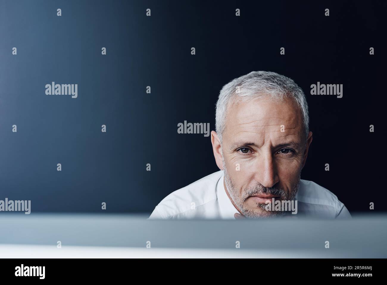 You can always find him behind his monitor. a mature businessman working on his computer Stock ...