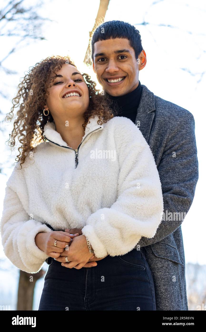 Two happy people of different genders embracing while they make a ...