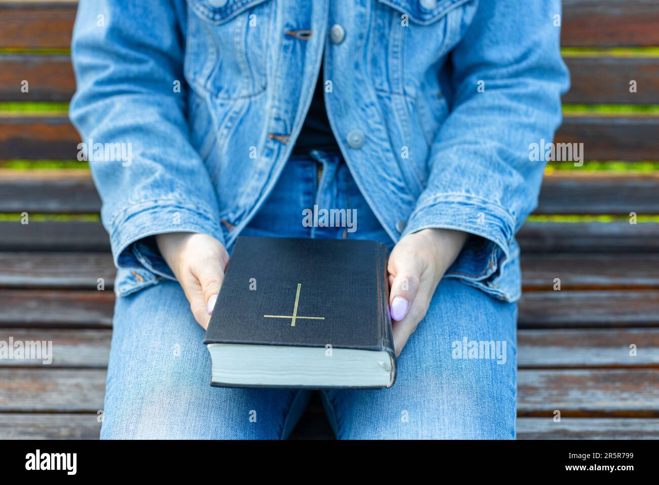 woman holding a bible sitting on a bench.closed bible in hands Stock ...
