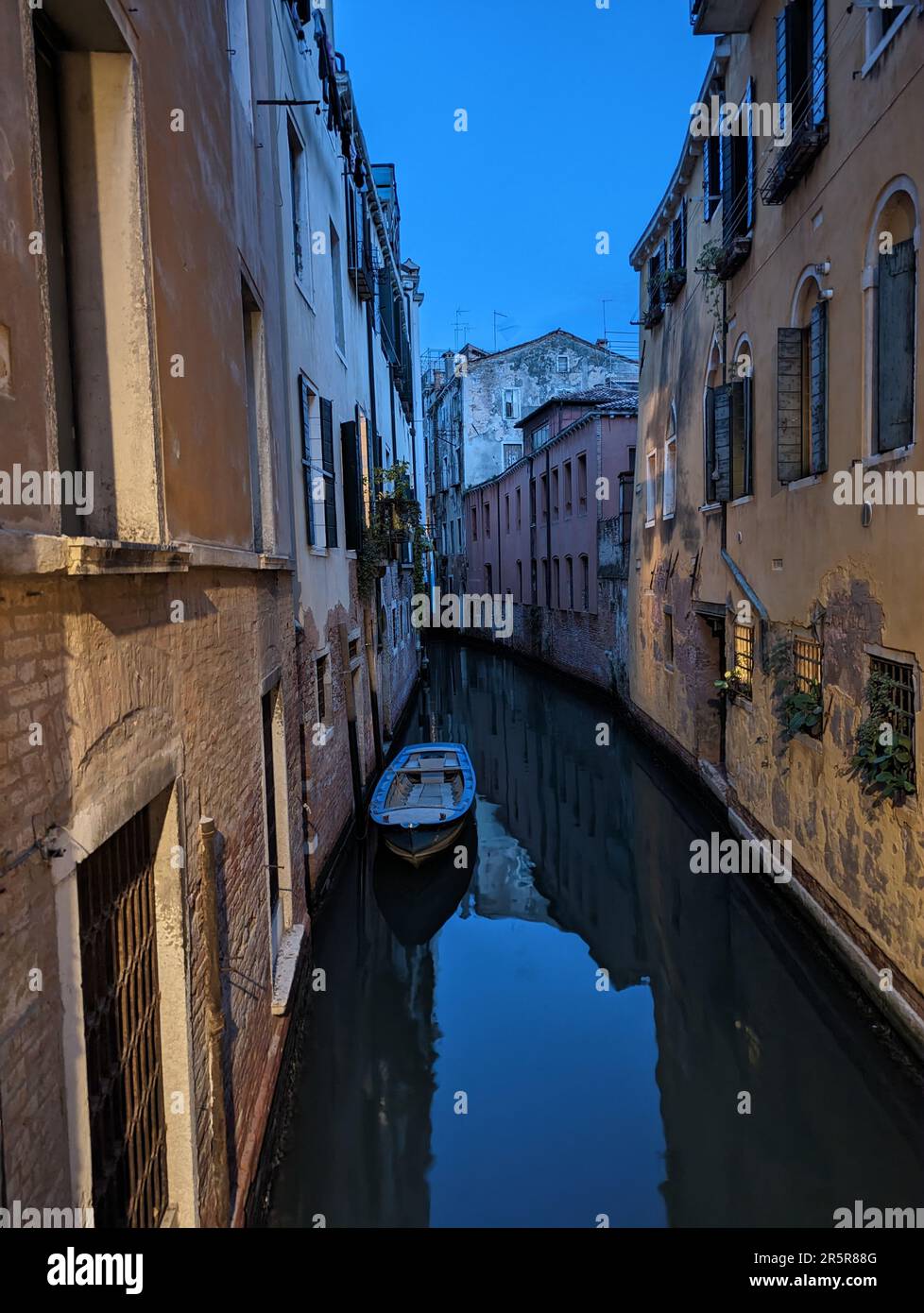 A boat floats down a narrow waterway, located beneath a house Stock ...