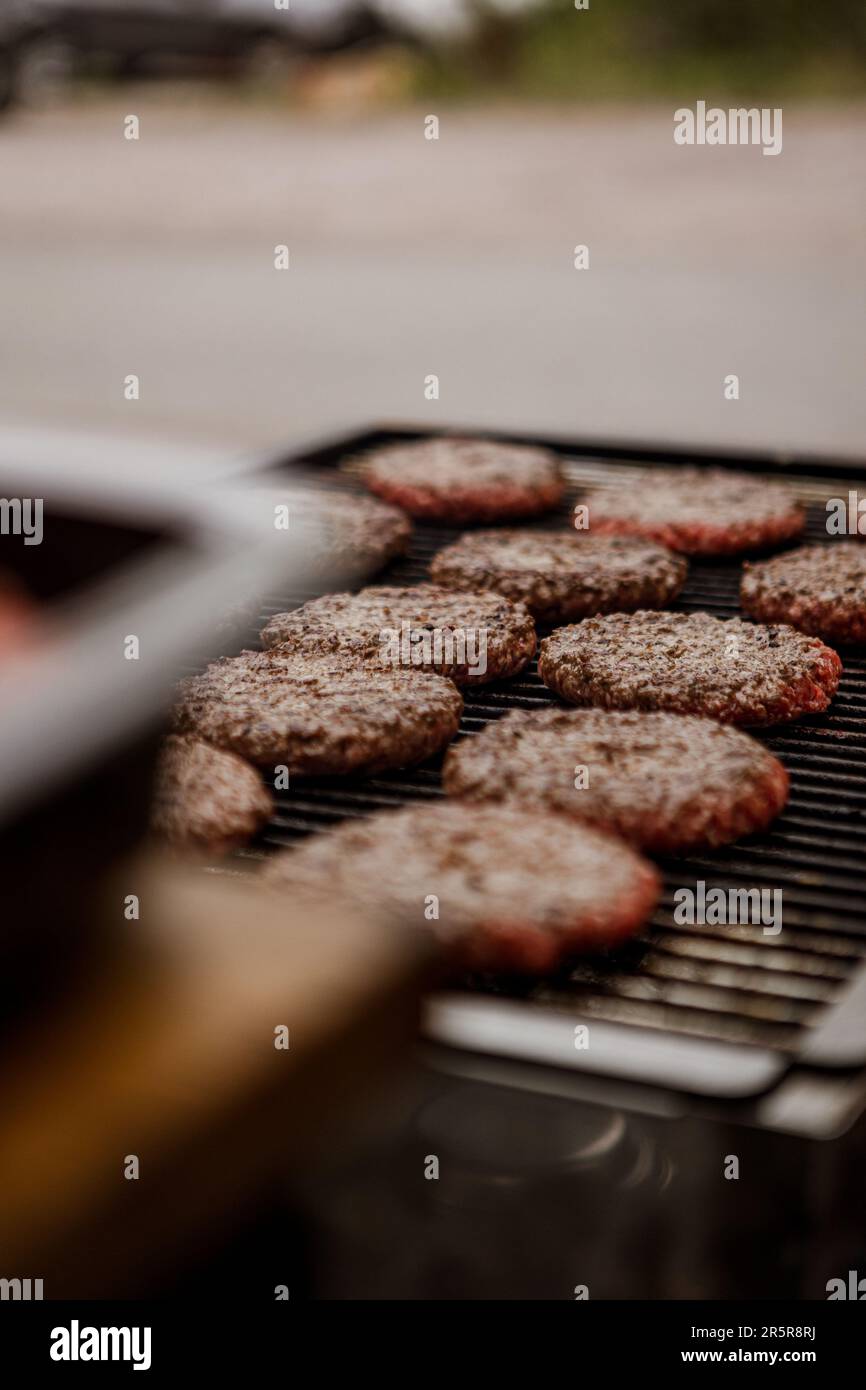 Three small hamburgers sizzle on a hot grill, each one surrounded by a ...