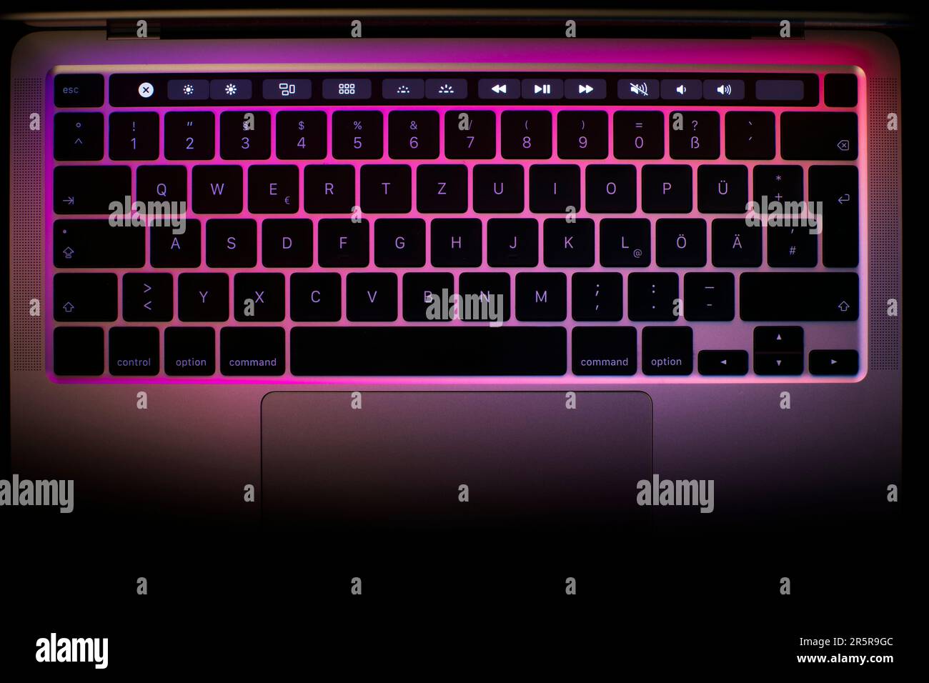 Top view of an illuminated pink and purple keyboard of a MacBook Pro in ...