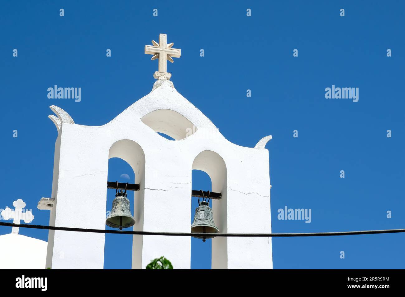 A cross and bells on the top of an orthodox whitewashed church in Ios ...