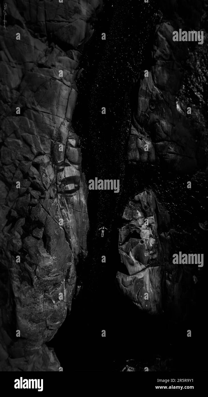 a black and white picture of rocks around a river with a person ...