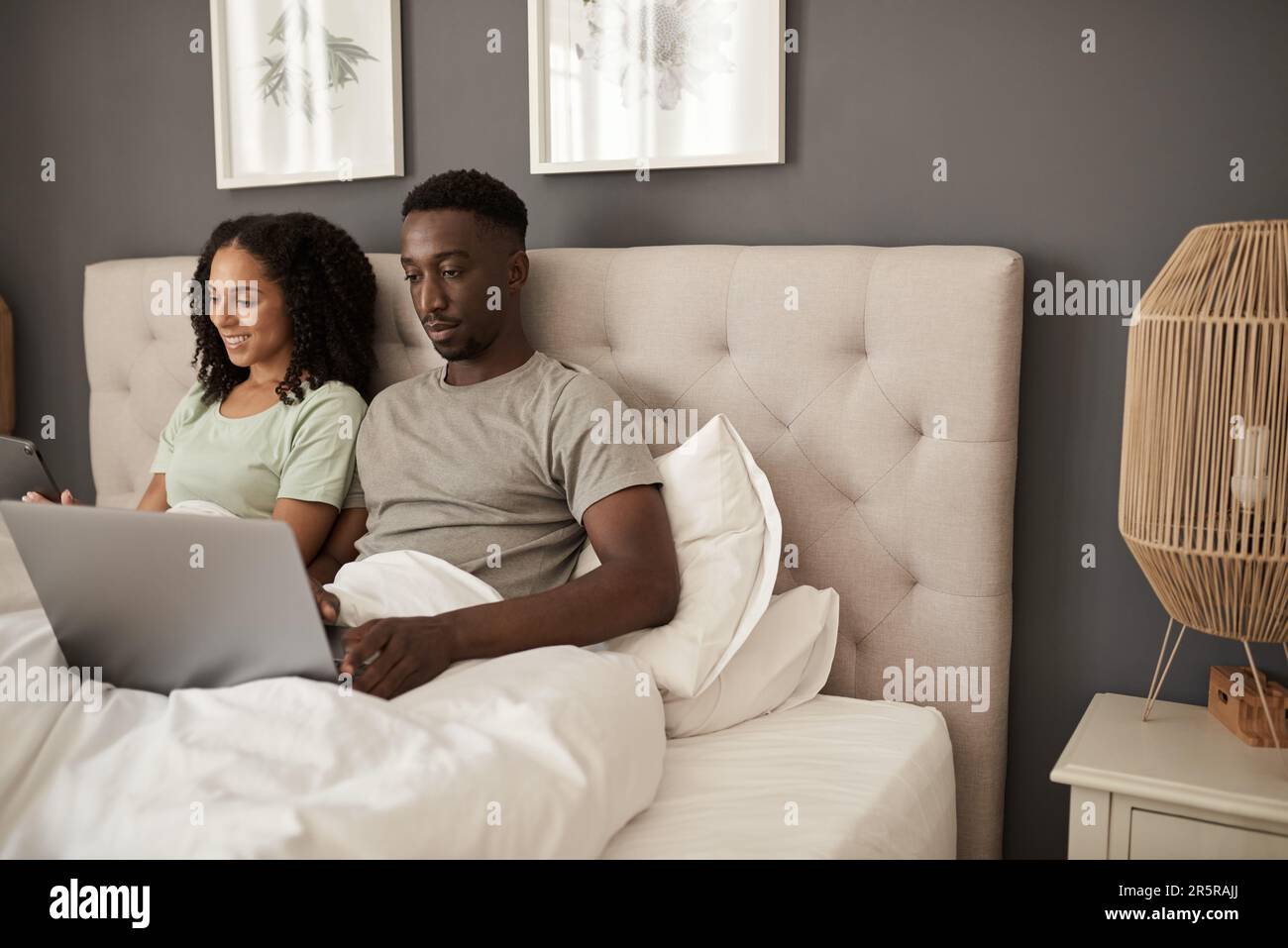 Young multiracial couple using different devices in their bed Stock ...