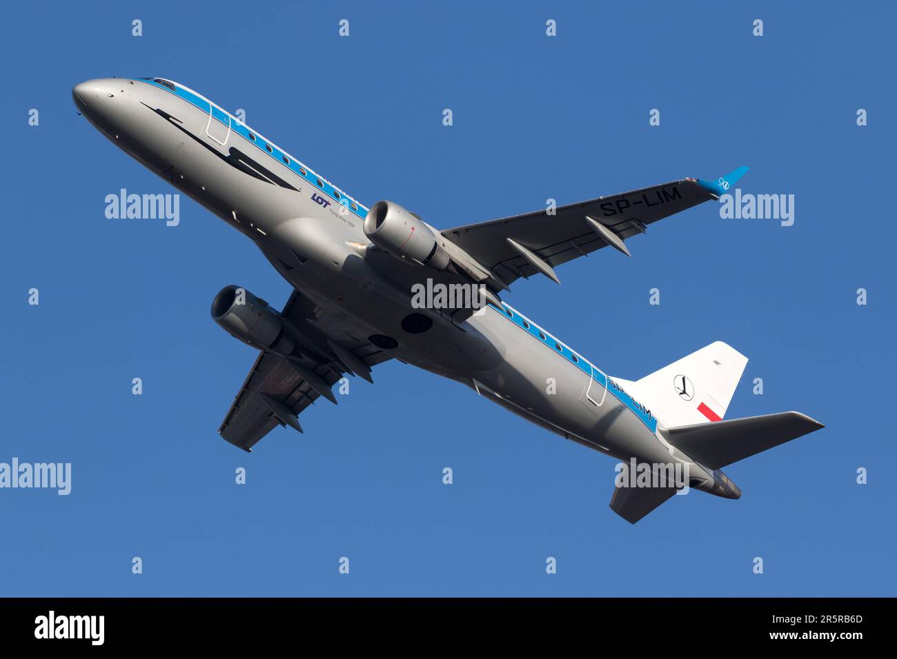 A single airplane soars through the vibrant blue sky, passing over a ...