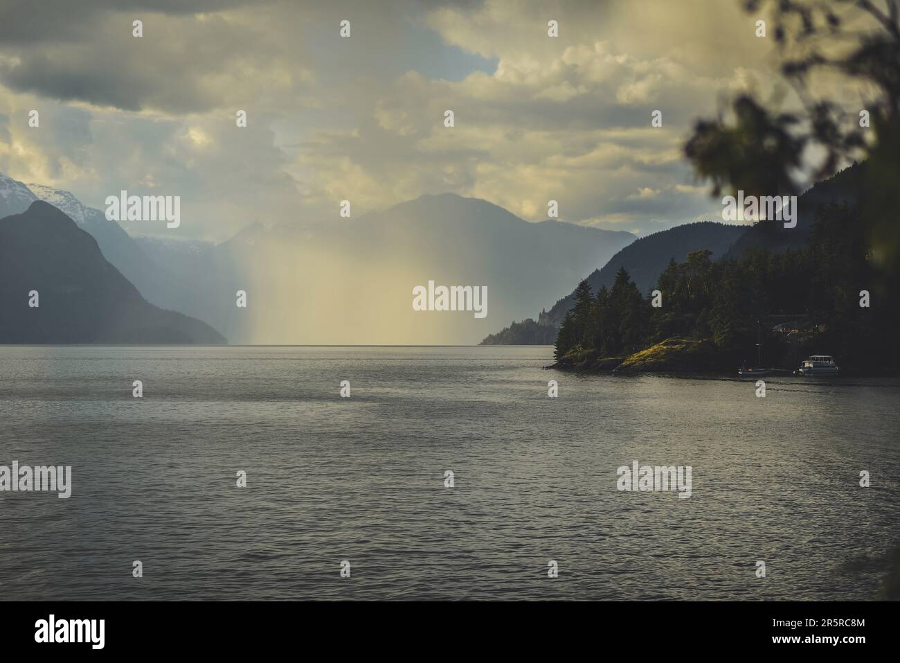 Rain pouring from clouds over calm water in Howe Sound viewed from ...