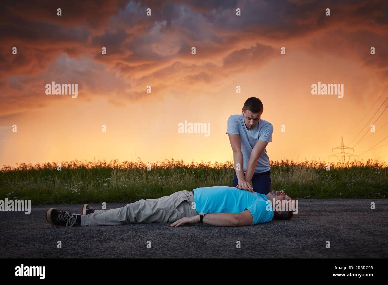 Dramatic resuscitation on rural road. Young man provides first aid to ...