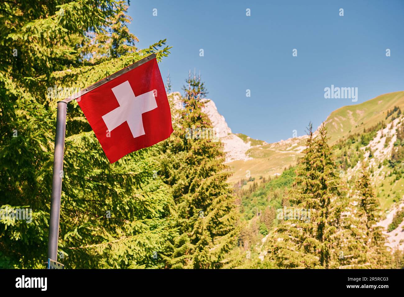 Swiss flag flies against the background of Alpine mountains Stock Photo ...