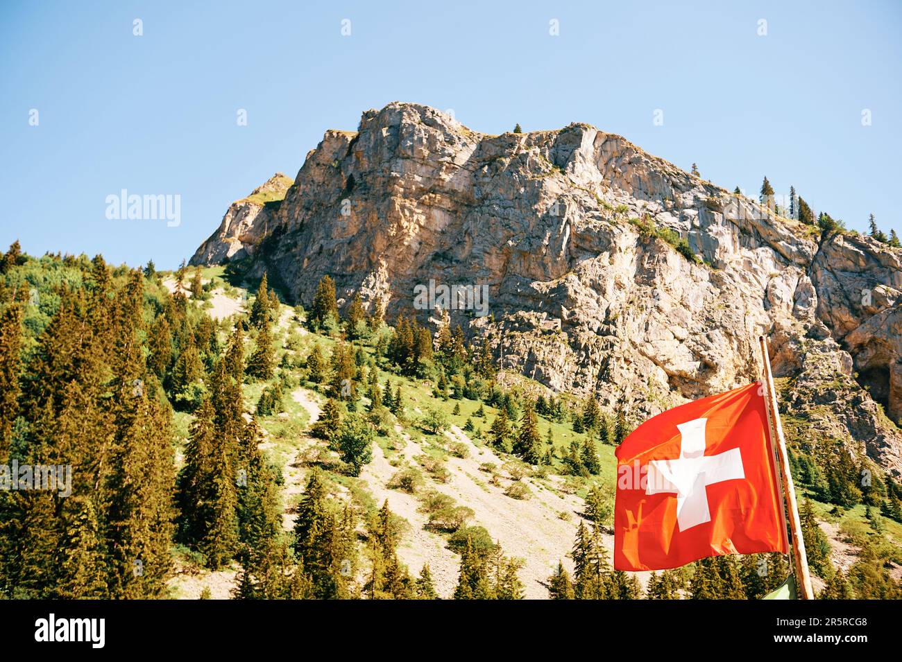 Swiss flag flies against the background of Alpine mountains Stock Photo ...