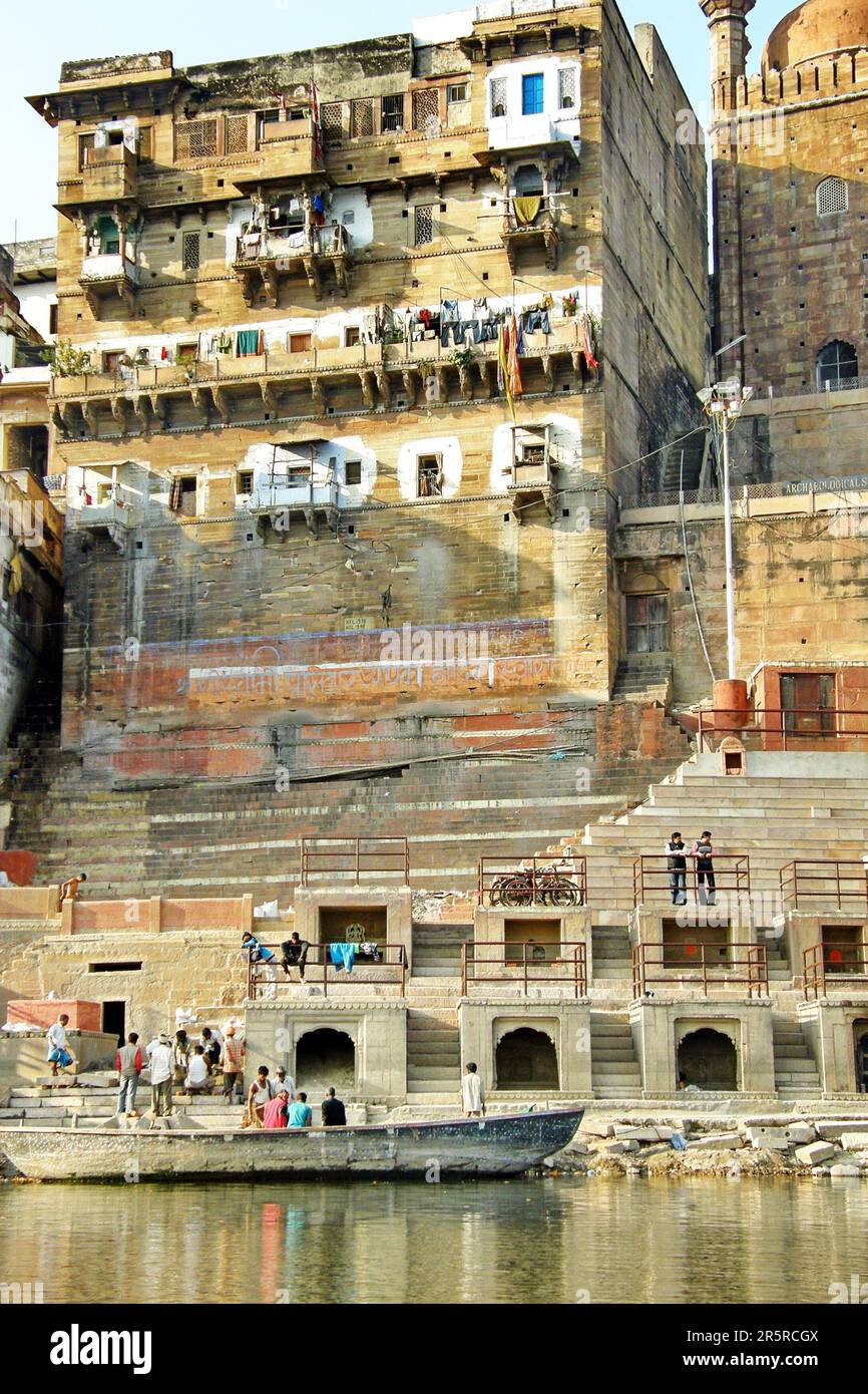 An old tall building near a river, with a large crowd of people ...