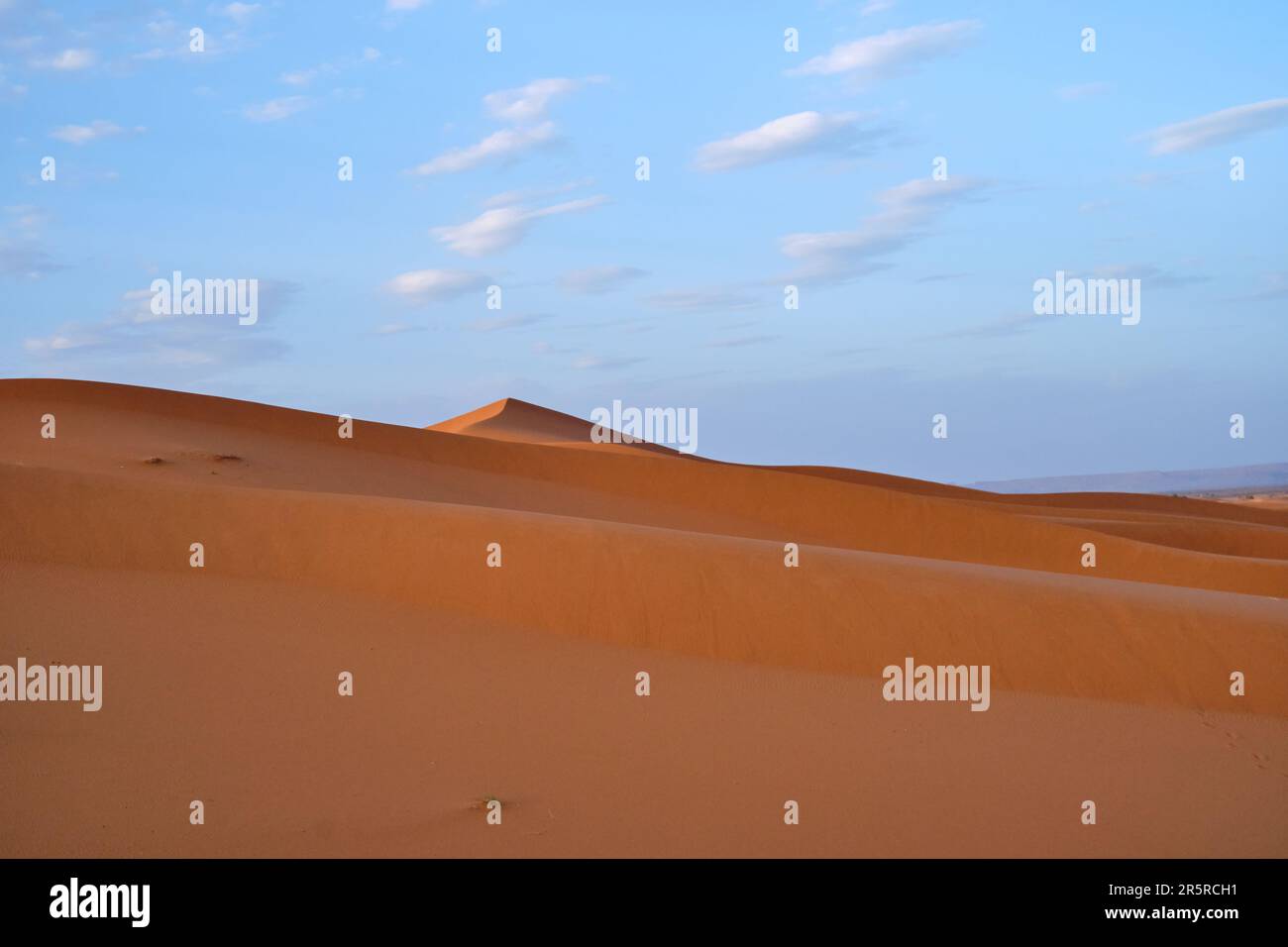 A stunning view of a sandy desert dune surrounded by a clear blue sky ...