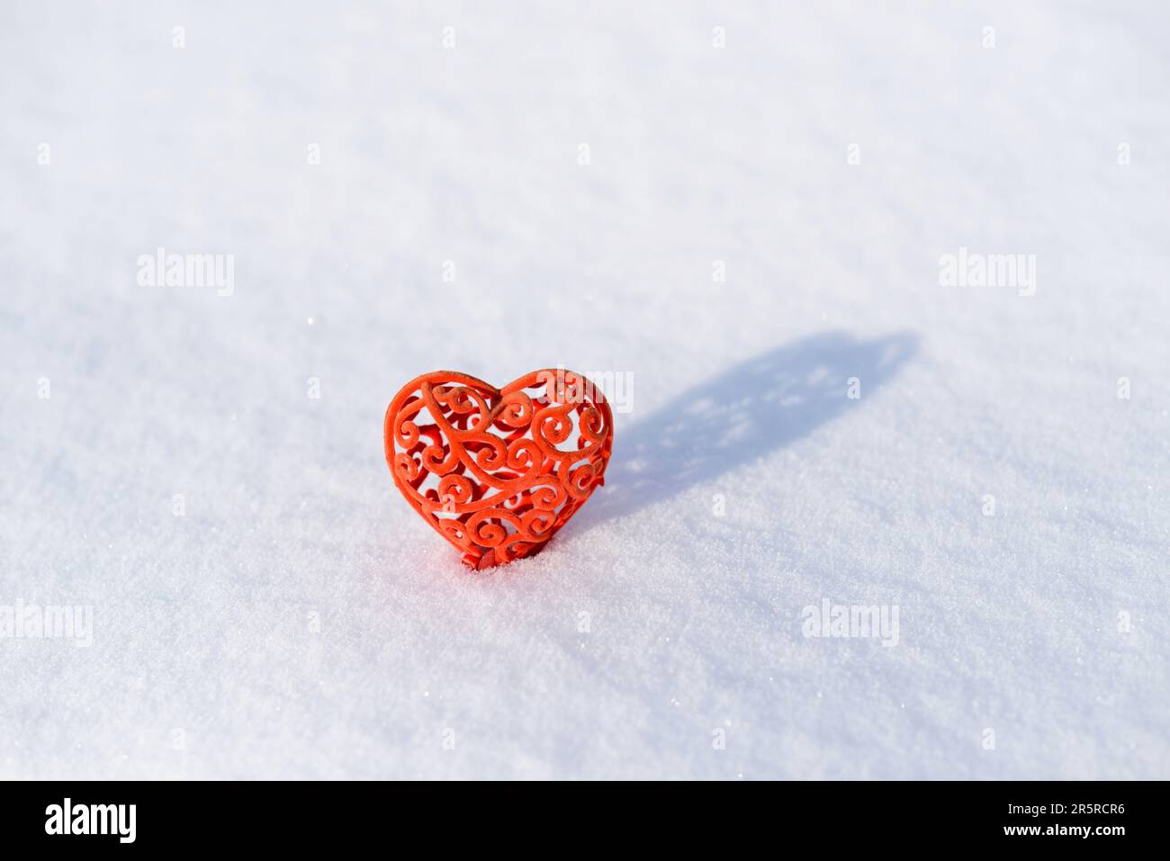 A red velvet heart, symbol of romantic love on a snowy background or ...