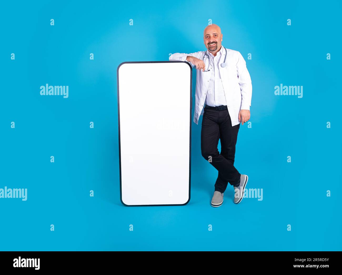 Middle aged doctor leaning big smartphone for application advertisement ...