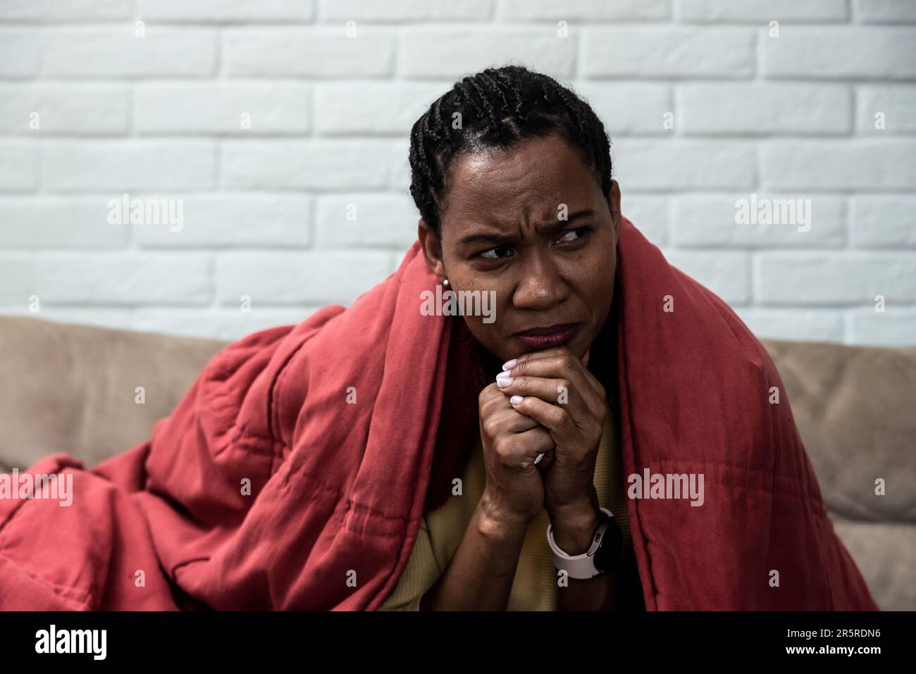 African American woman sitting at home wrapped in blanket crying ...
