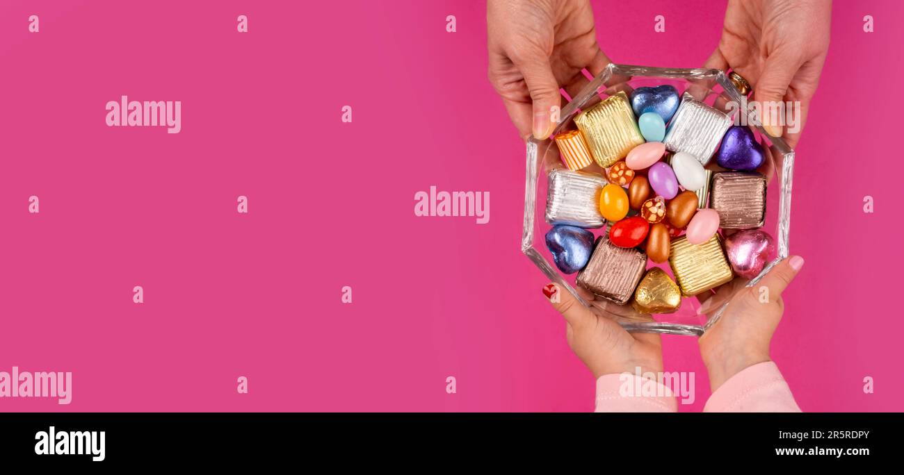 Mother and daughter hands holding bowl of candies. Top view, isolated ...