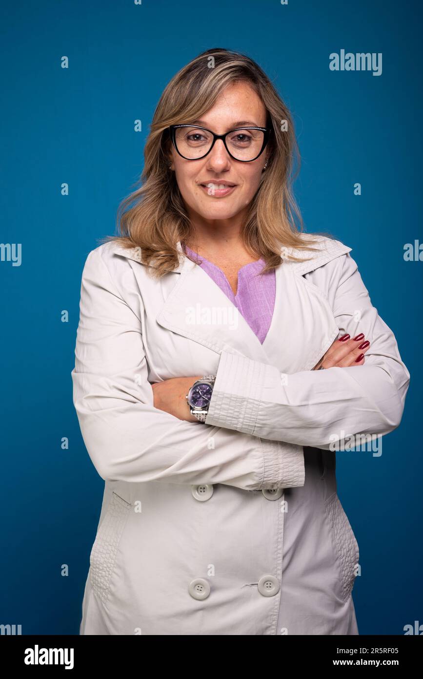 Confident female nurse dressed in beige colored coat wearing eyeglasses ...