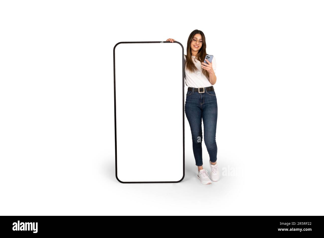Using mobile phone while leaning big smartphone mockup. Full body length caucasian young woman ...