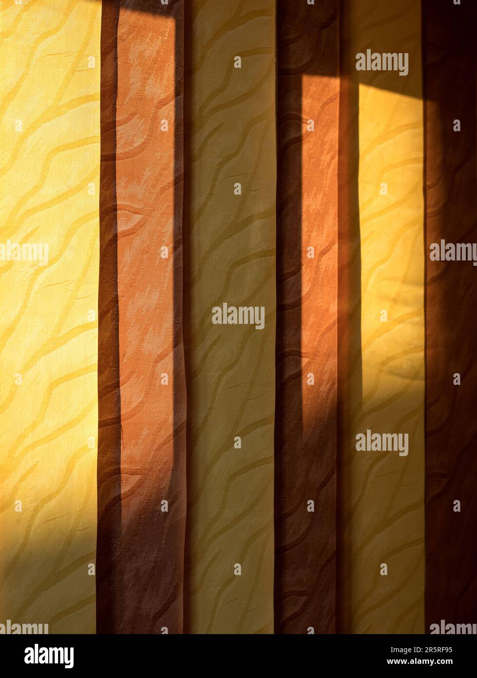 A variety of brightly-colored neckties are illuminated in a sunlit ...