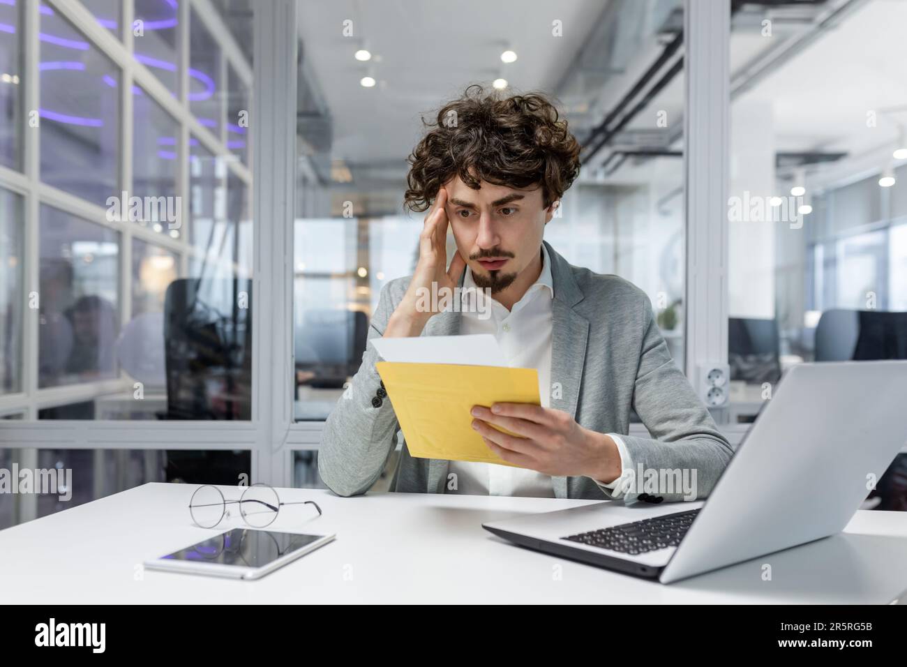 Sad and upset mature businessman received an envelope by mail with a ...