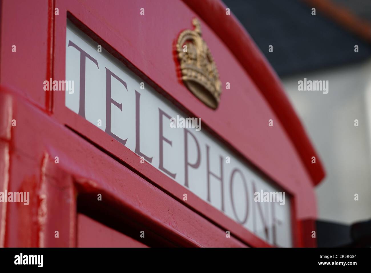 A vintage red telephone box stands in front of a white building, adding ...
