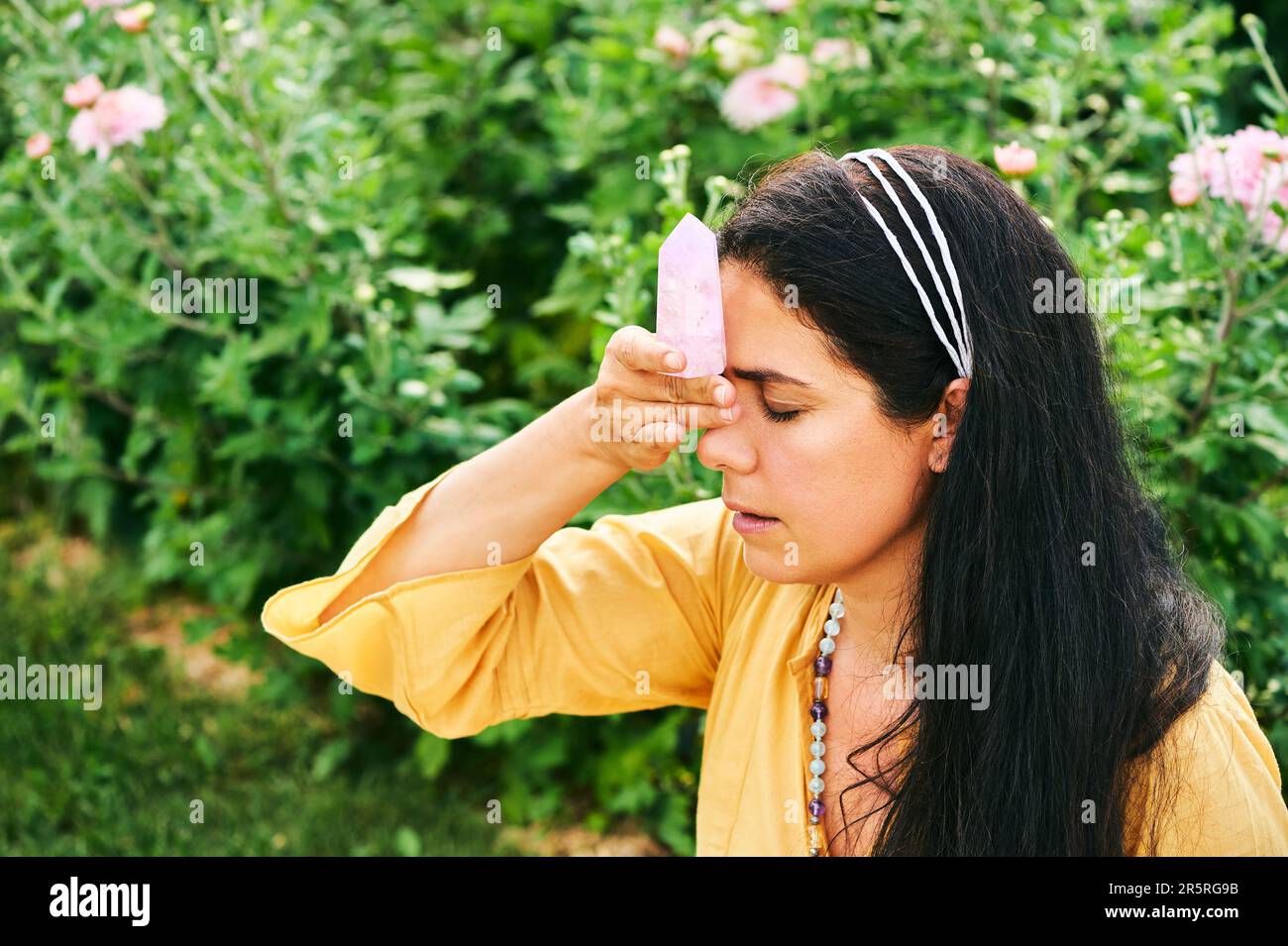 Woman healer holding natural mineral kunzite next to head Stock Photo ...