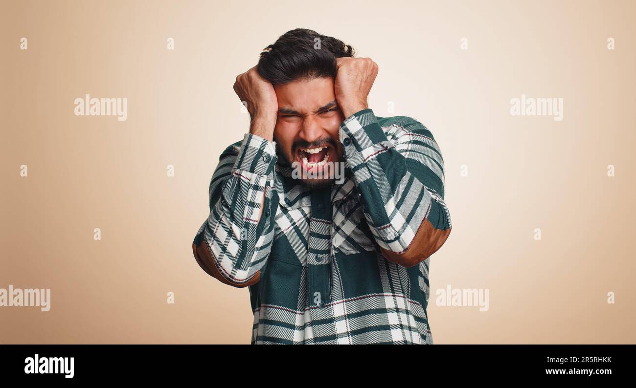 Young indian man scared fearful, covering ears with hands, closing eyes ...