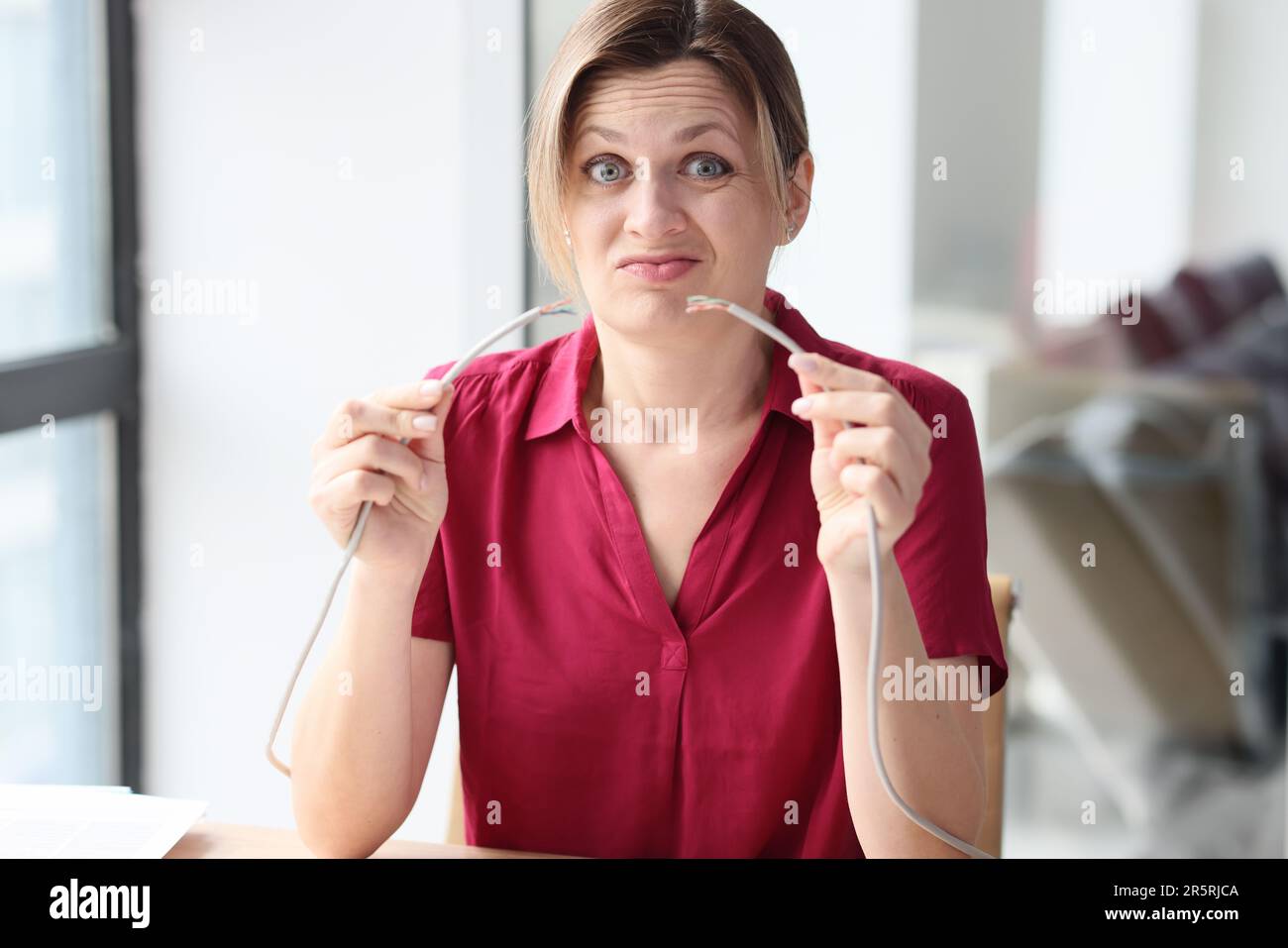Doubting woman holds teared internet wire sitting at table Stock Photo ...