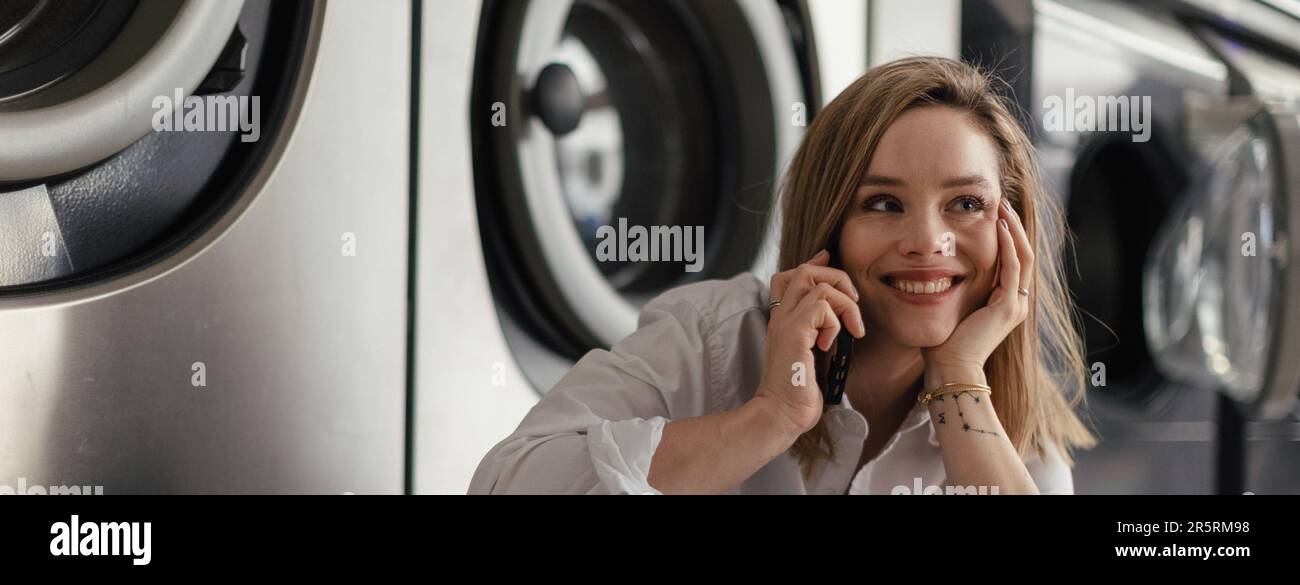 Young woman calling, waiting in a laundry room Stock Photo - Alamy