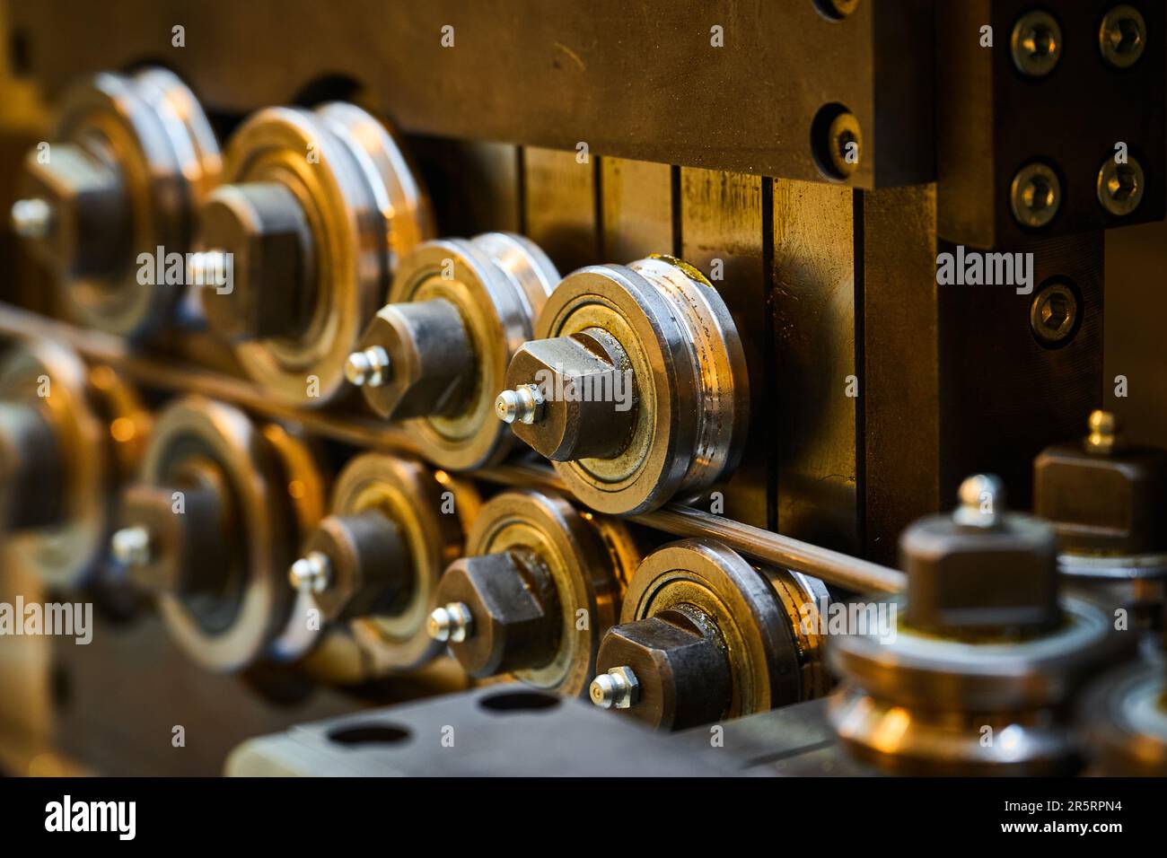 Metal cable pulled out through rollers line on machine tool Stock Photo ...