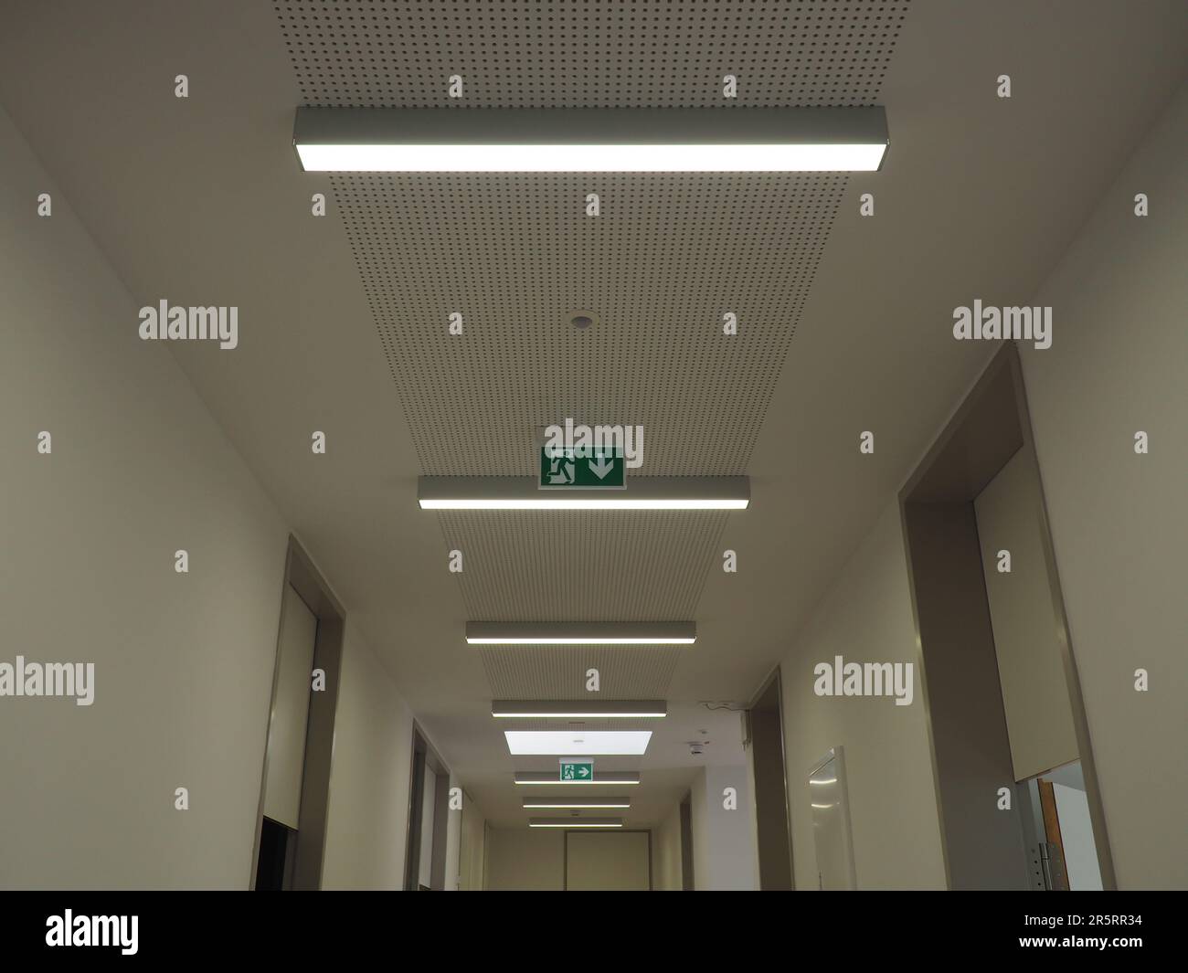An interior hallway with a sign pointing to the exit Stock Photo - Alamy