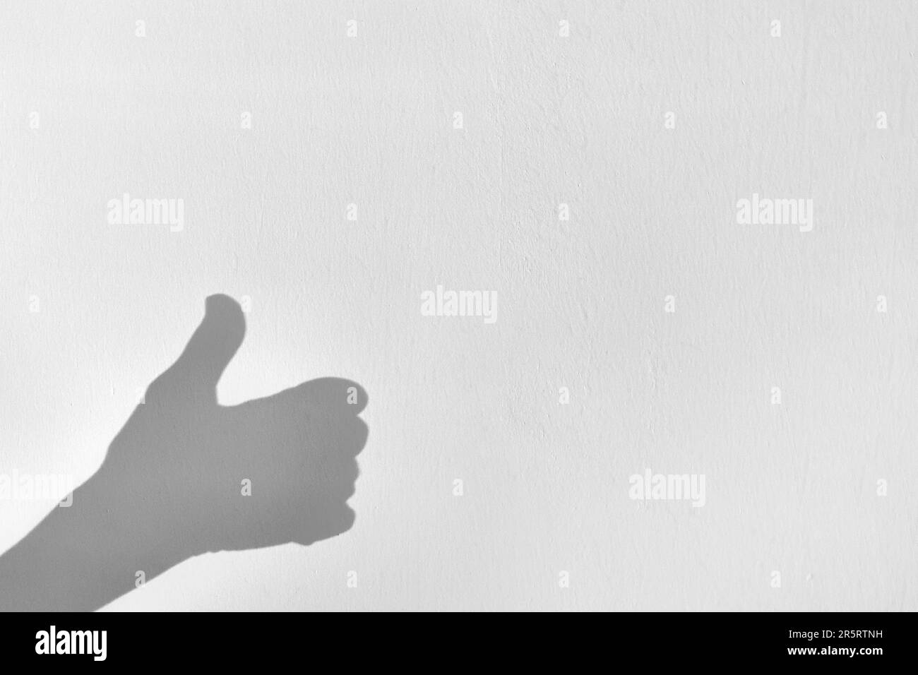 Shadow silhouette of hand with thumb raised up on gray background ...